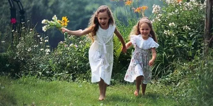 Girls run barefoot on the grass