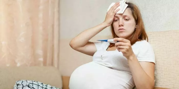 Gravid kvinna med termometer i handen