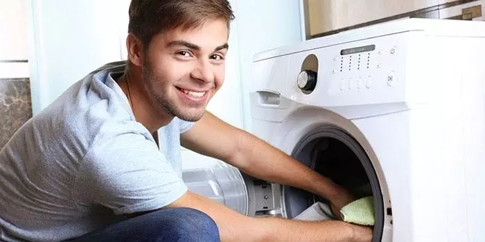 הבחור מכניס דברים לתוף מכונת הכביסה