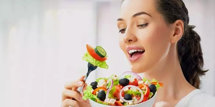 Jenta spiser grønnsaksalat i henhold til dietten for slanking av bein og hofter