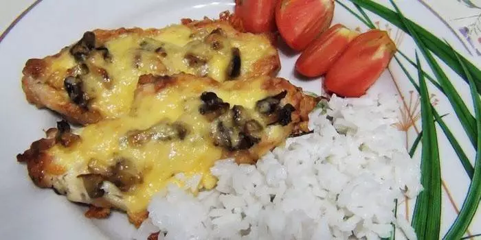 Costeletas prontas com cogumelos e queijo e arroz cozido em um prato