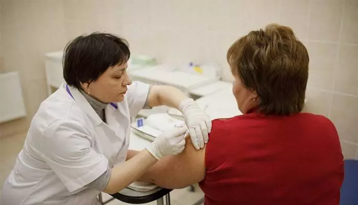 O femeie este vaccinată în umăr