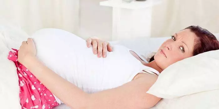Gruaja shtatzënë e shtrirë në shtrat