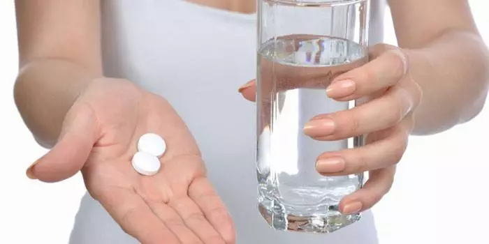 Tabletas y un vaso de agua.