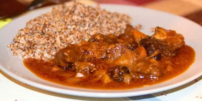 Beef meat in sweet and sour sauce with prunes and buckwheat porridge