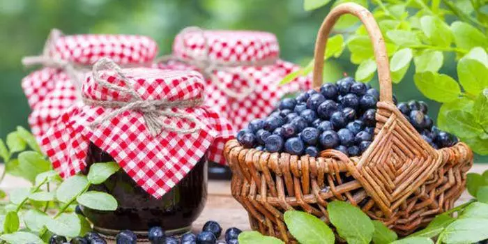 Blueberryjam yn krûden en farske bosbessen op 'e tafel