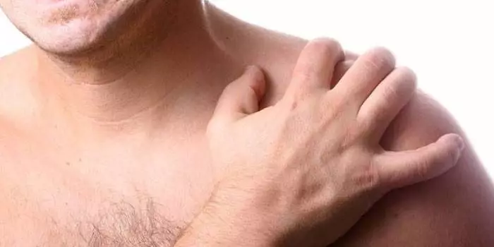 Ein Mann hält seine Schulter mit seiner Hand