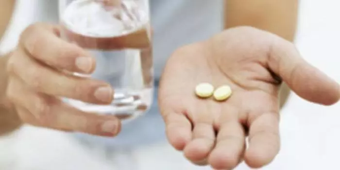 Tablete in kozarec vode v rokah
