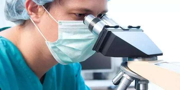 Lægen kigger gennem mikroskopet