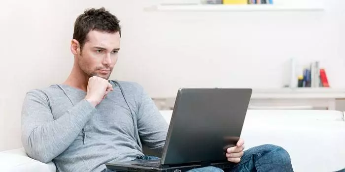 A man sitting on a sofa with a laptop