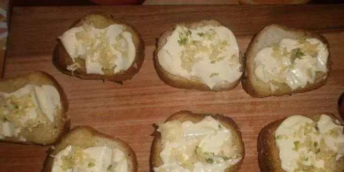 Croutons parod gyda mayonnaise a garlleg ar fwrdd torri