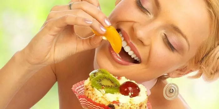 Mergaitė valgo pyragą ir vaisius