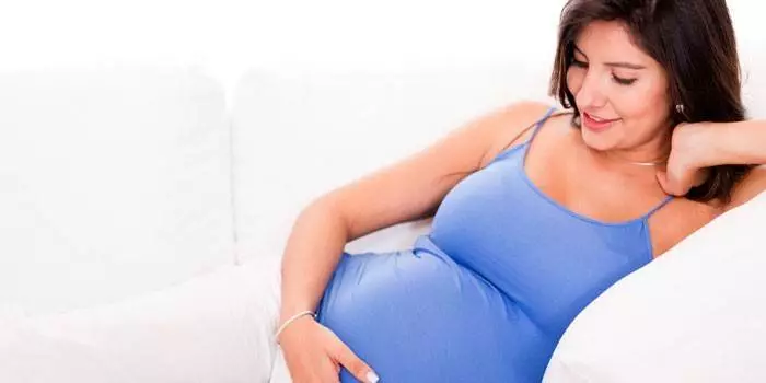 Gravid kvinne som ligger på sofaen
