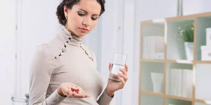 Girl with pills and a glass of water in her hands