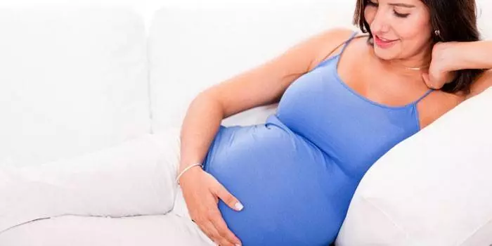 Бремена девојка лежи на каучот