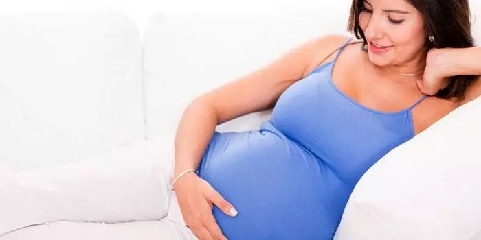 Fată gravidă întinsă pe canapea
