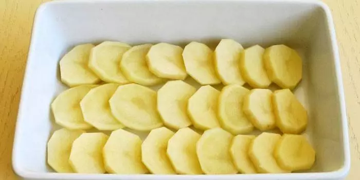 Isang layer ng mga hiwa ng hilaw na patatas sa hugis ng
