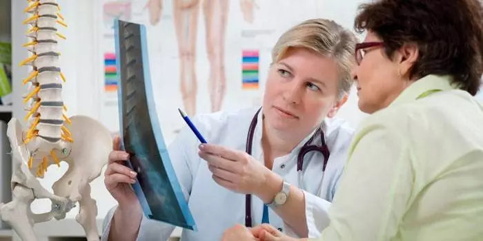 Médico com um paciente examinando um raio-X