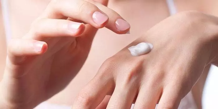 La ragazza applica la crema sulla pelle delle sue mani