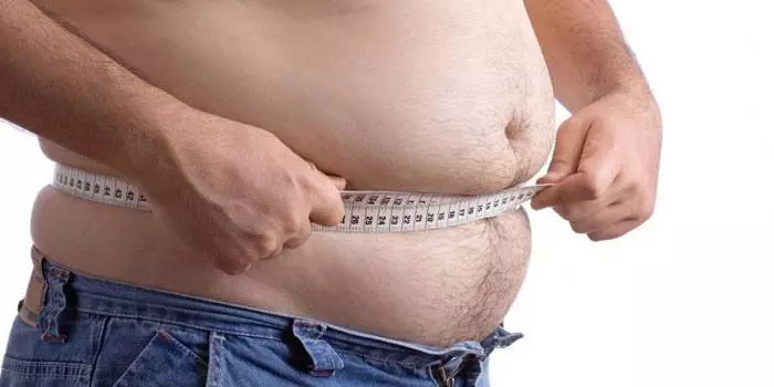 A man measures his belly with a centimeter