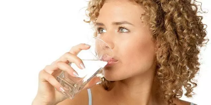 Το κορίτσι πίνει νερό από ένα ποτήρι