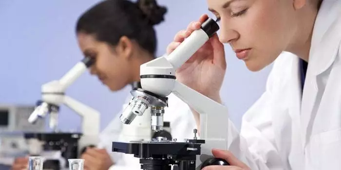 Uma garota olhando através de um microscópio