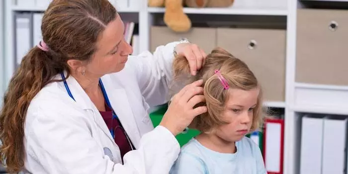 El médico examina la cabeza del niño.