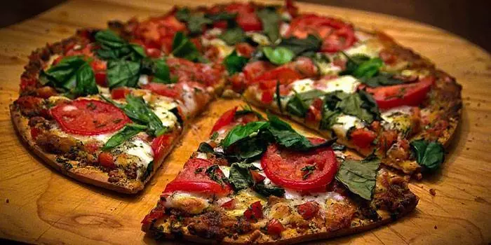 Pizza pachithunzi chochepa kwambiri chodzaza ndi tomato ndi mozzarella ndi basil