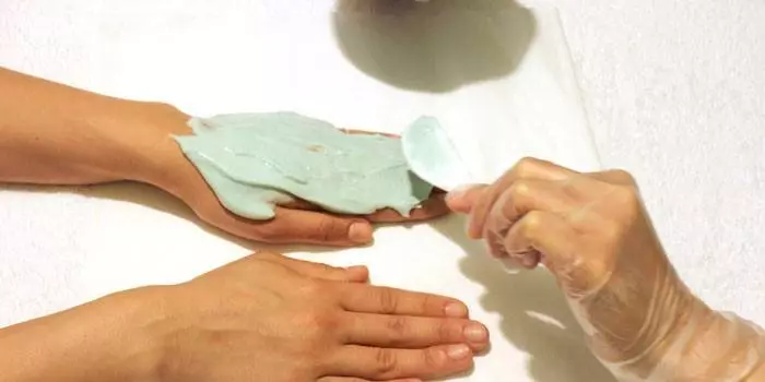 A girl is made a clay mask for her hands