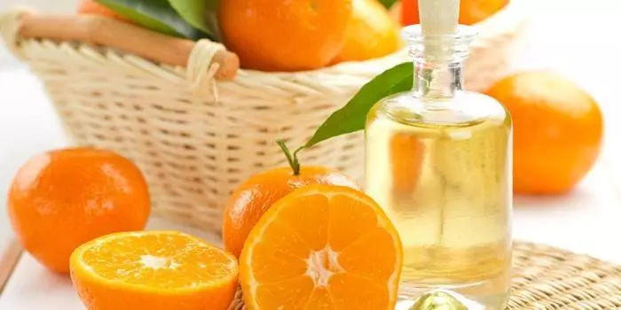 Pomerančový olej ve sklenici a pomeranče