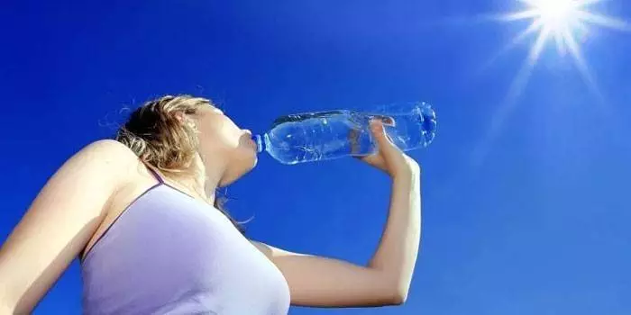 La fille boit de l'eau d'une bouteille