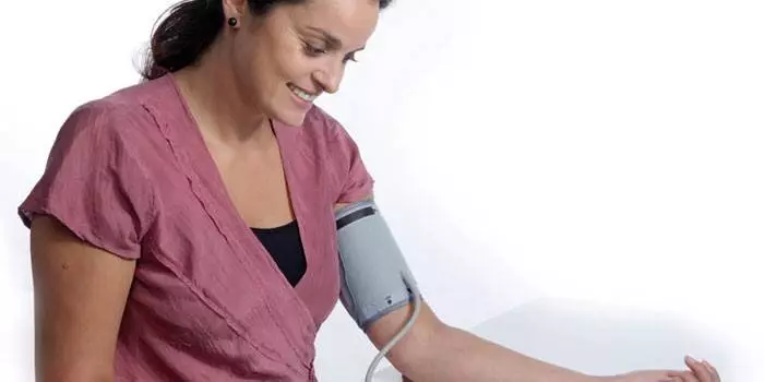 Kvinnan mäter sitt blodtryck