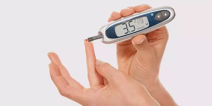 ልጅቷ የደም ስኳርን በ glucometer ይለካል