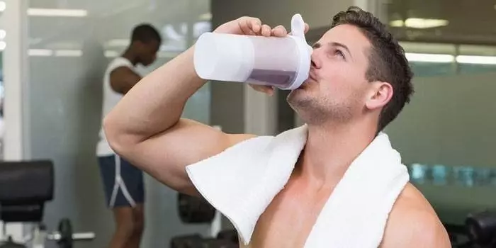 Hombre en el gimnasio bebiendo un batido de proteínas