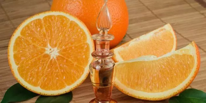 Етерично масло од портокал во шише и исечен портокал