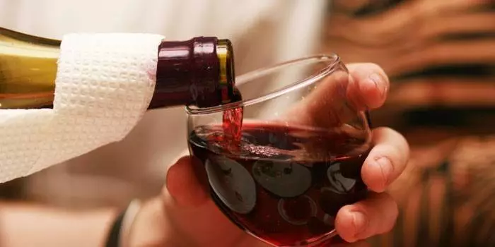 Rotwein wird aus einer Flasche in ein Glas gegossen