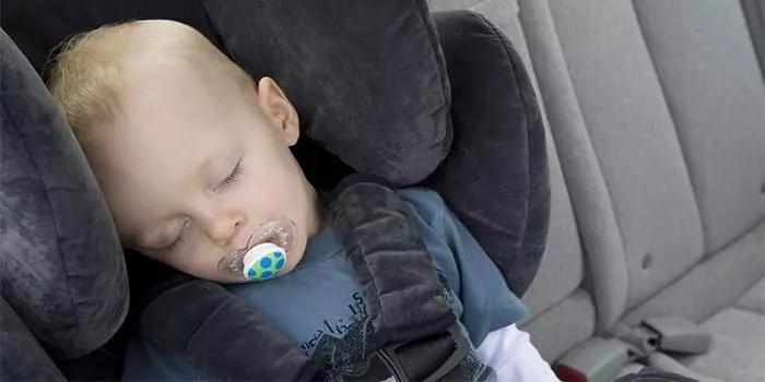 孩子闭着眼睛坐在汽车座椅上