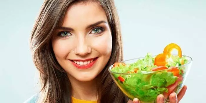 Девојка држи тањир салате