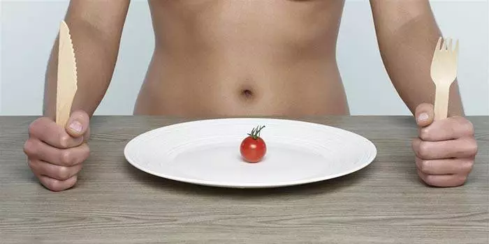 テーブルの上の女の子と皿の上の小さなトマト