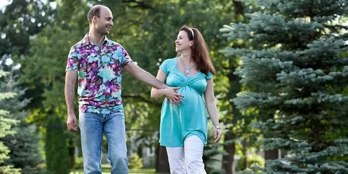 Бремена жена со сопругот на прошетка во паркот