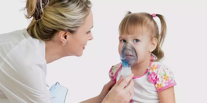 Gydytojas prie vaiko veido laiko deguonies kaukę