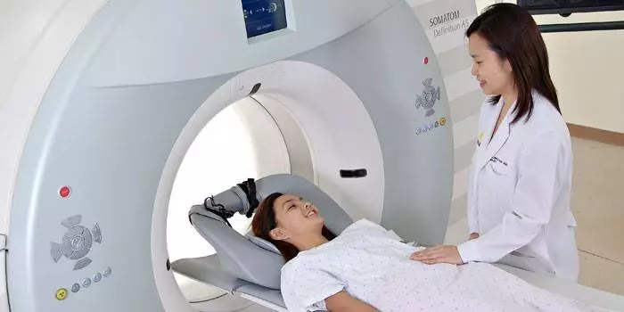 The girl in the tomograph talks to the doctor before the examination