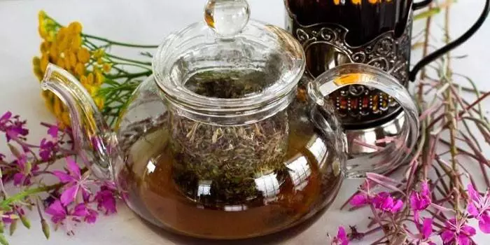 Teapot with herbal tea and herbs