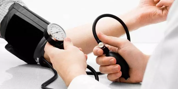O médico mide a presión arterial cun tonómetro