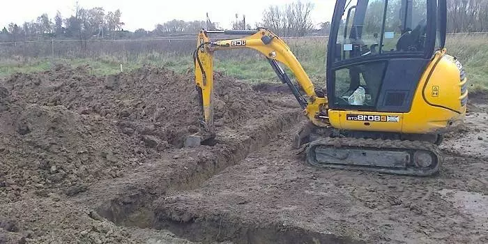 Excavator digs trenches on site