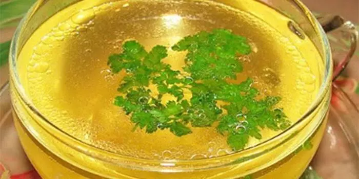 Light chicken broth with parsley in a cup