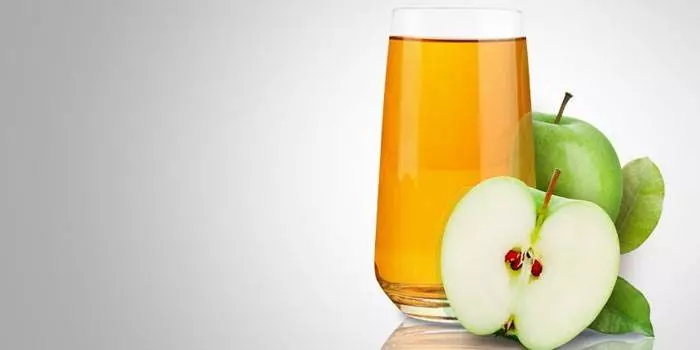 Äppeljuice i ett glas och äpplen