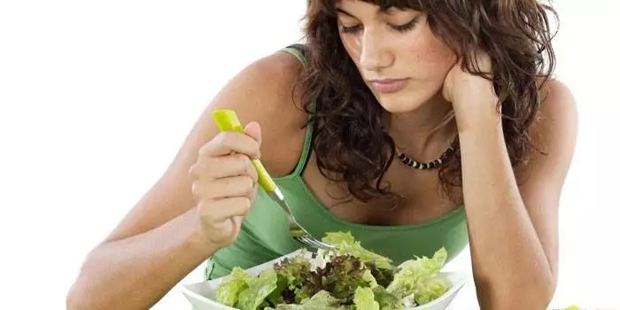Sieviete skatās uz salātu šķīvi