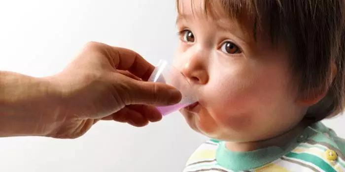 A gyermek gyógyszert kap egy mérőpohárban