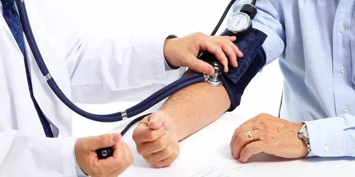 Ārsts mēra asinsspiedienu ar tonometru